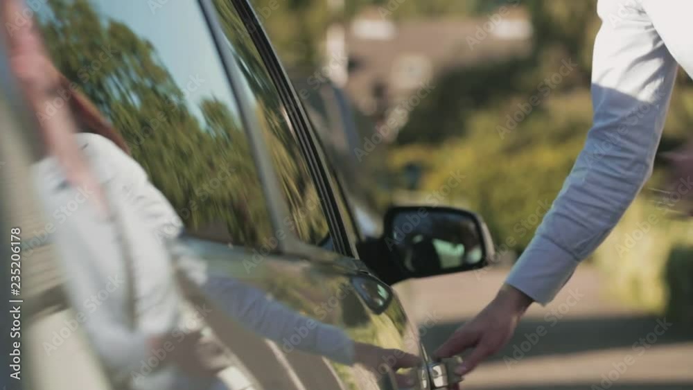 A young female passenger or a driver unlocks a parked car and gets in ...