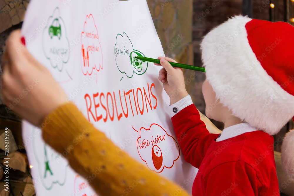 Young kid child boy in red santa hat making his resolution goals for ...