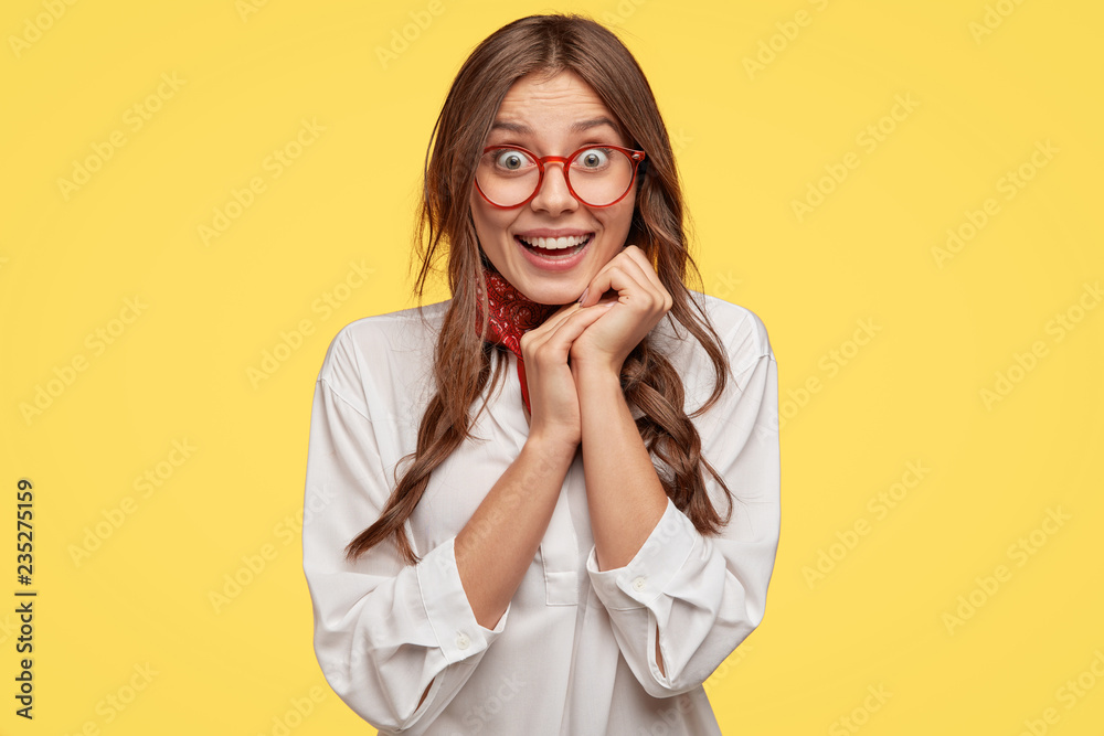 Pretty satisfied lady expresses good feelings, keeps hands together ...