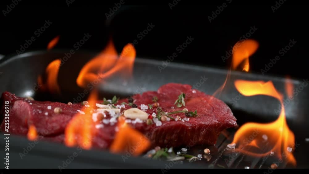Super slowmotion footage of flambe fresh beef meat and seasoning on ...