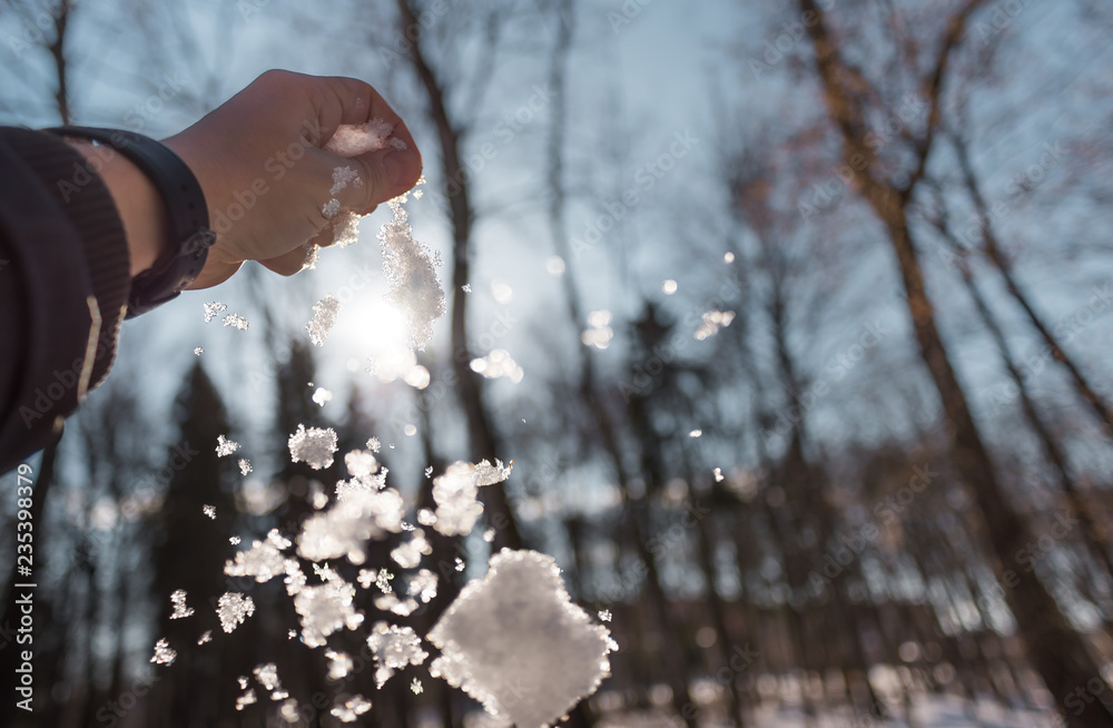 A caucasian man's hand squeezing a snowball flying into pieces and ...