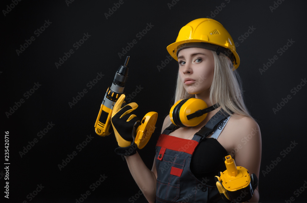 girl in construction clothes and protective equipment posing with a ...