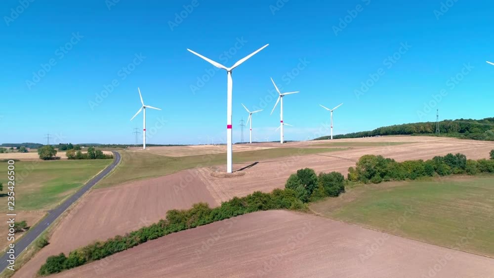 Aerial video of rotary wind turbines over dry fields in germany ...