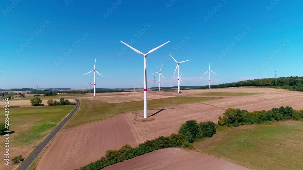 Aerial video of rotary wind turbines over dry fields in germany ...