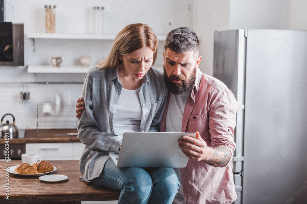 confused young couple looking at laptop screen at kitchen Stock Photo ...