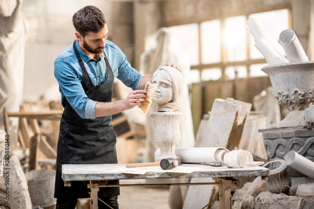 Handsome sculptor brushing sculpture of the woman's head at the working ...