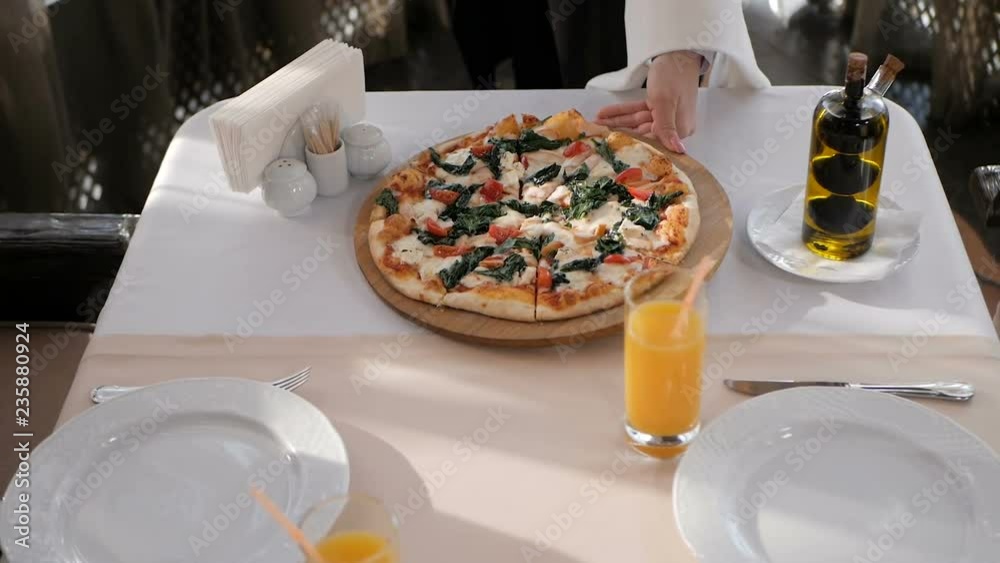 Waiter puts pizza on the table in the restaurant Stock Video | Adobe Stock