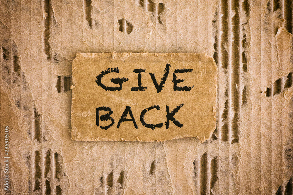 Piece of cardboard with words Give Back on tattered corrugated ...