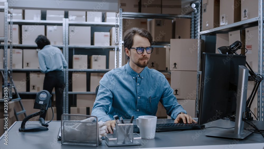 Foto de Warehouse Inventory Manager Works on Computer while Sitting at ...