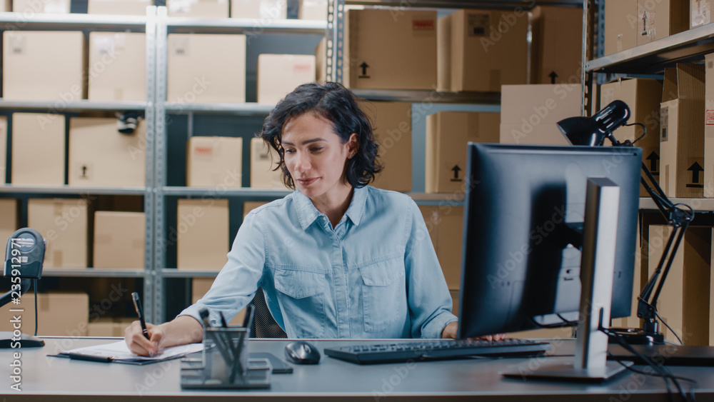 Female Inventory Manager Works on a Computer while Sitting at Her Desk ...