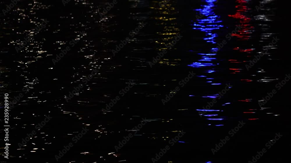 Colorful light reflections on surface of sea water at night time ...