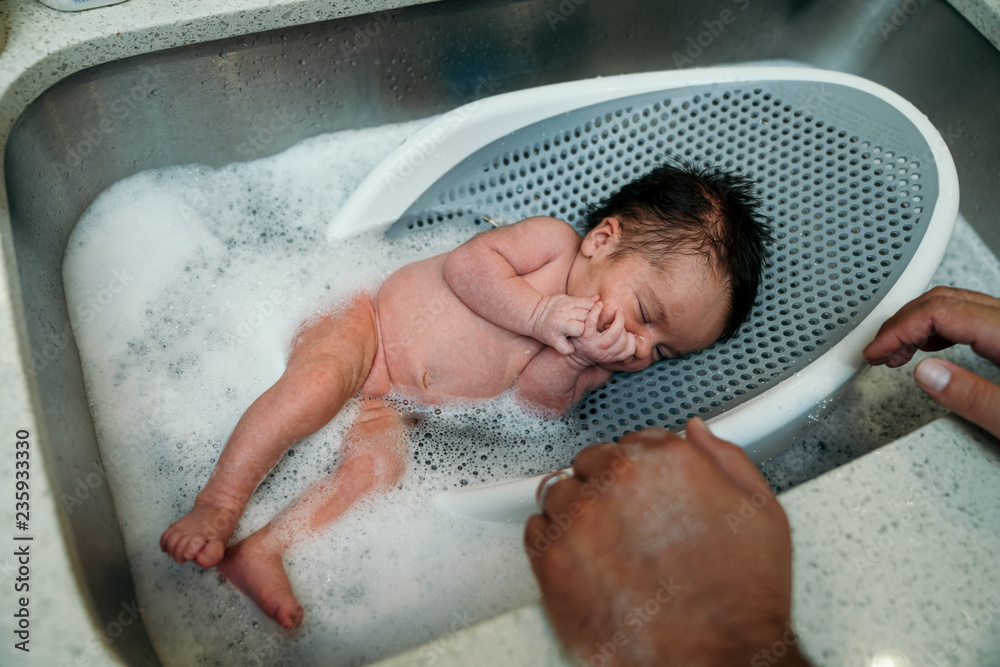 Baby girl having a bath in a basin in kitchen sink Stock Photo | Adobe ...