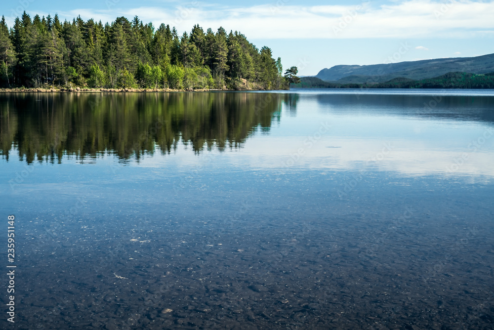 A quiet peaceful summer morning with view over crystal clear calm lake ...