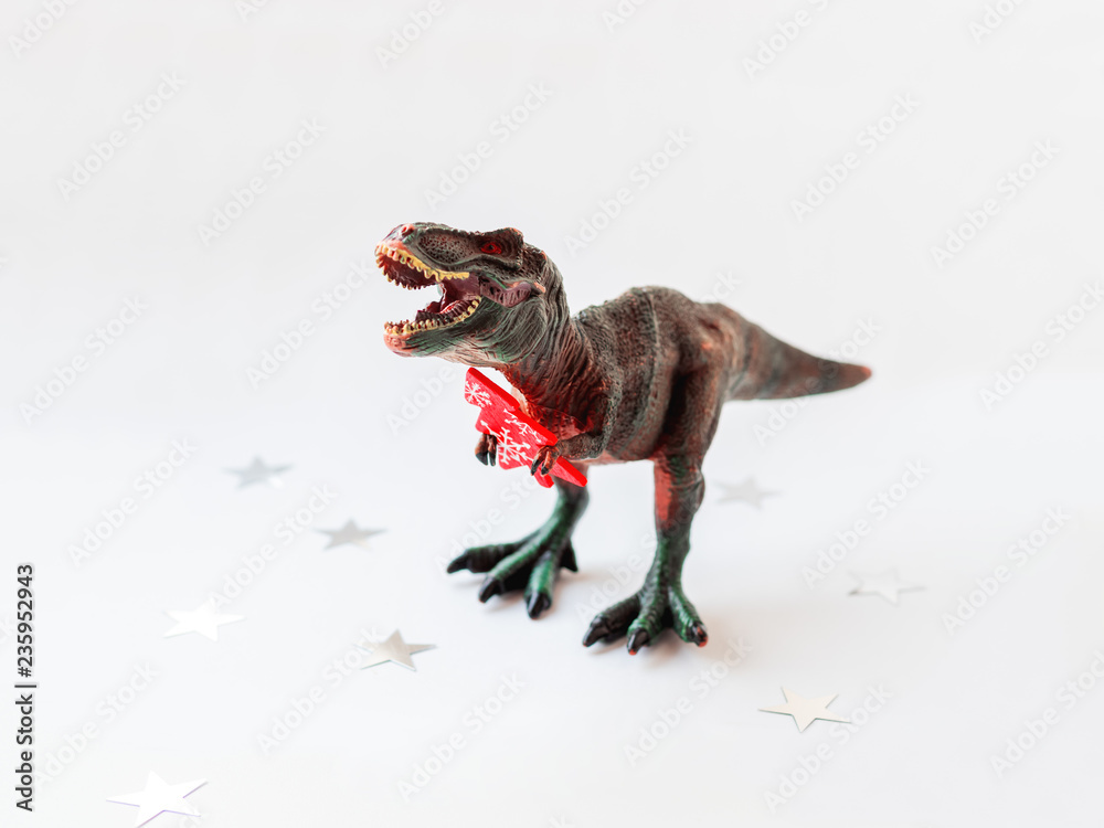 Dinosaur with red Christmas tree. Plastic toy with wooden symbol of ...