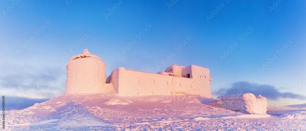 Epic snow capped structure of old observatory on the summit of mountain ...