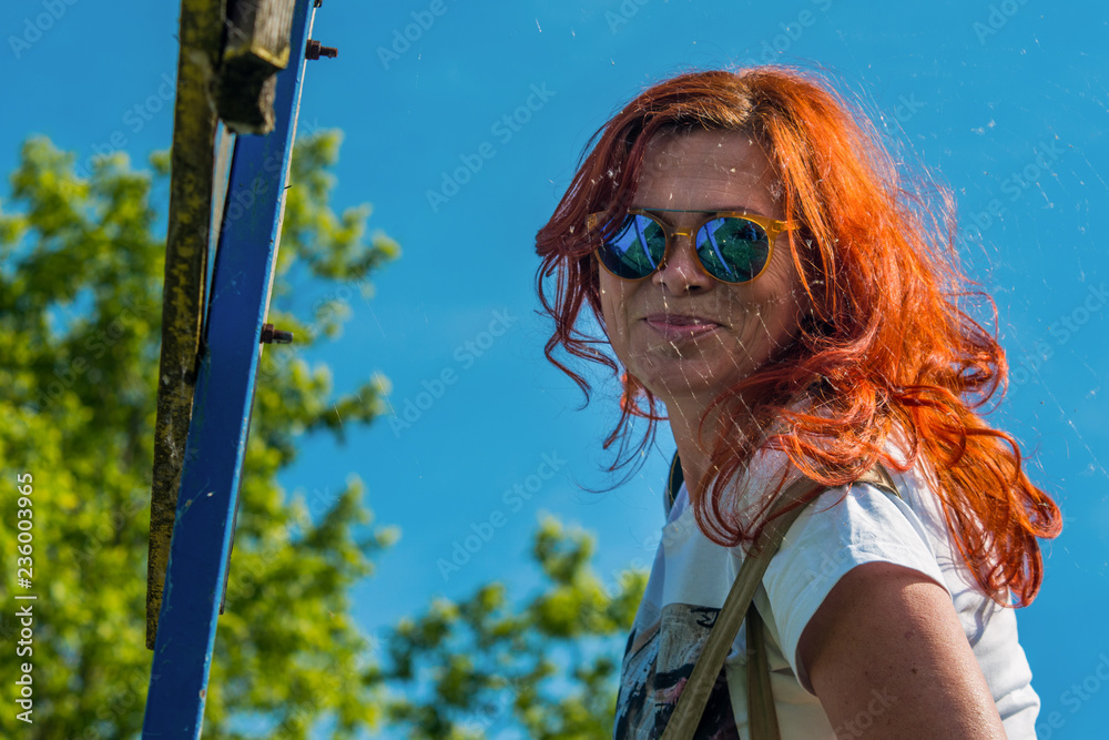 Spider woman. A middle-aged woman poses with orange hair and sunglasses ...