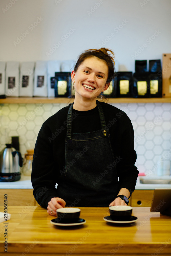 Vertical portrait of Friendly female barista with a two cups of coffee ...