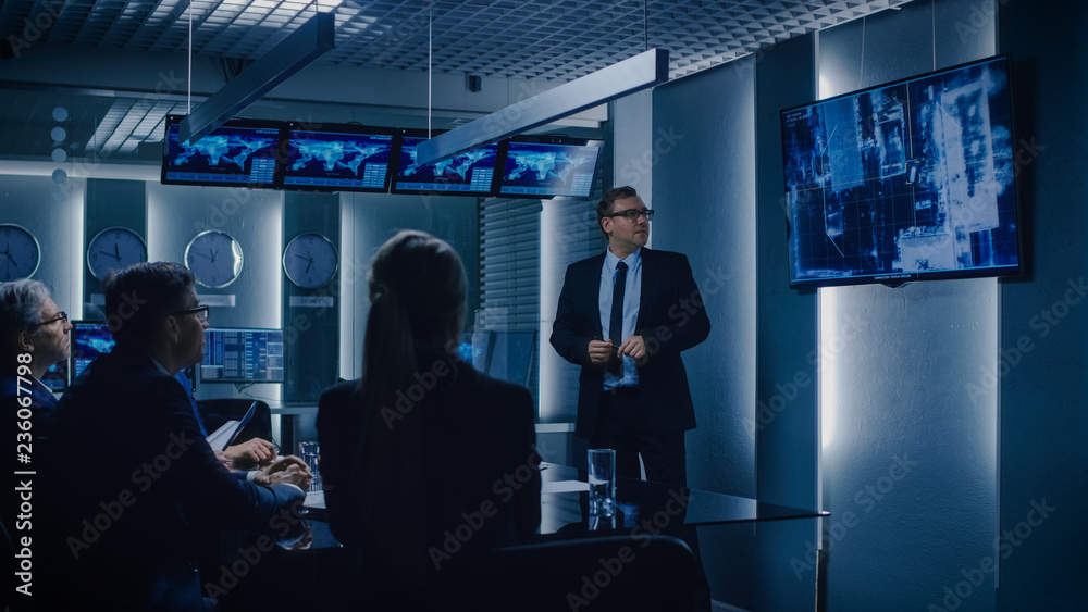 Chief of Operations Shows Surveillance Footage on Wall TV Screen to a ...