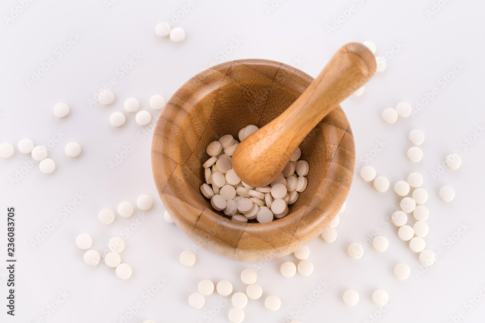 Close-up of small white tablets in a wooden mortar to be ground into ...