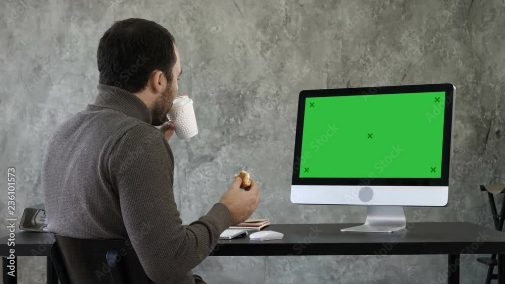 Young man choking while eating and watching something on the computer ...