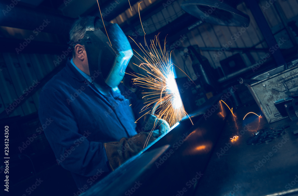 A vibrant action shot of a skilled working metal welder in action ...