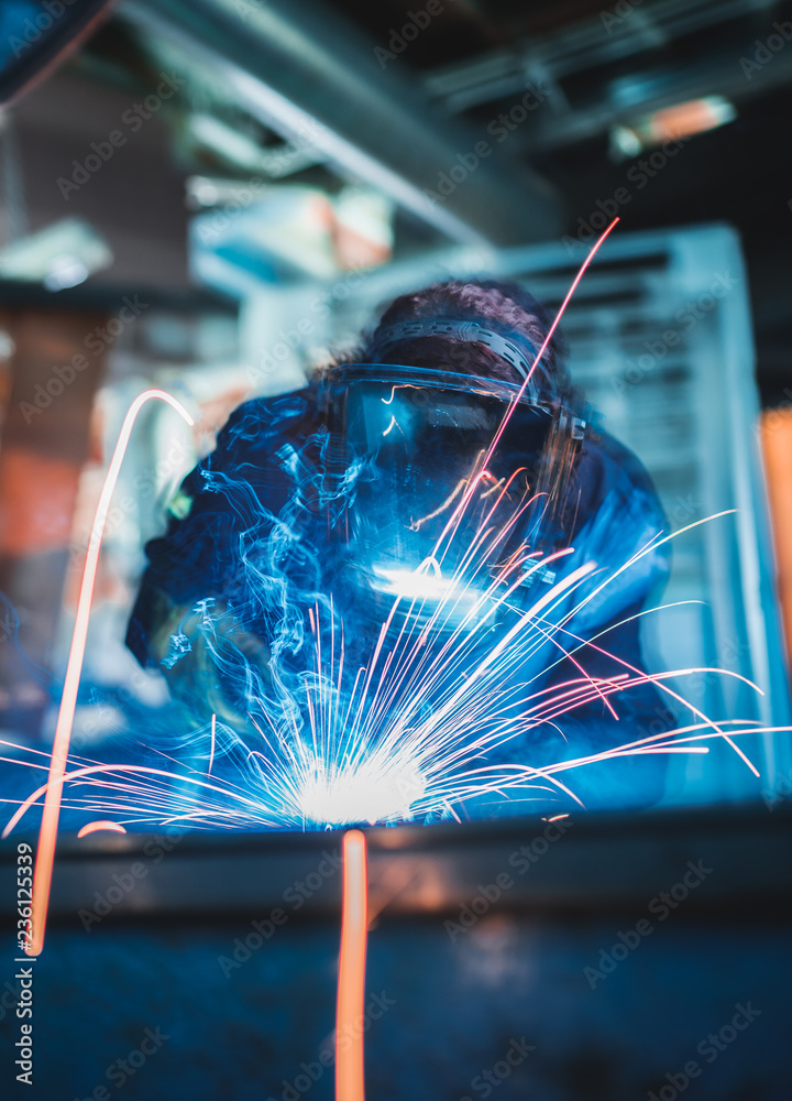 A vibrant action shot of a skilled working metal welder in action ...