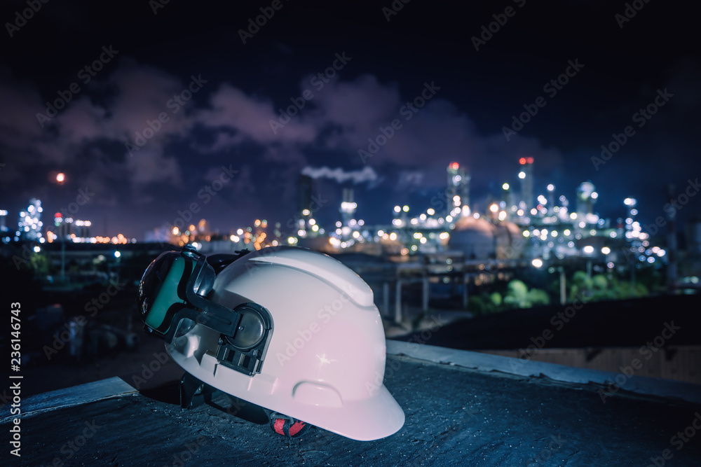 White safety helmet and ear muff on industrial plant background, Worker ...