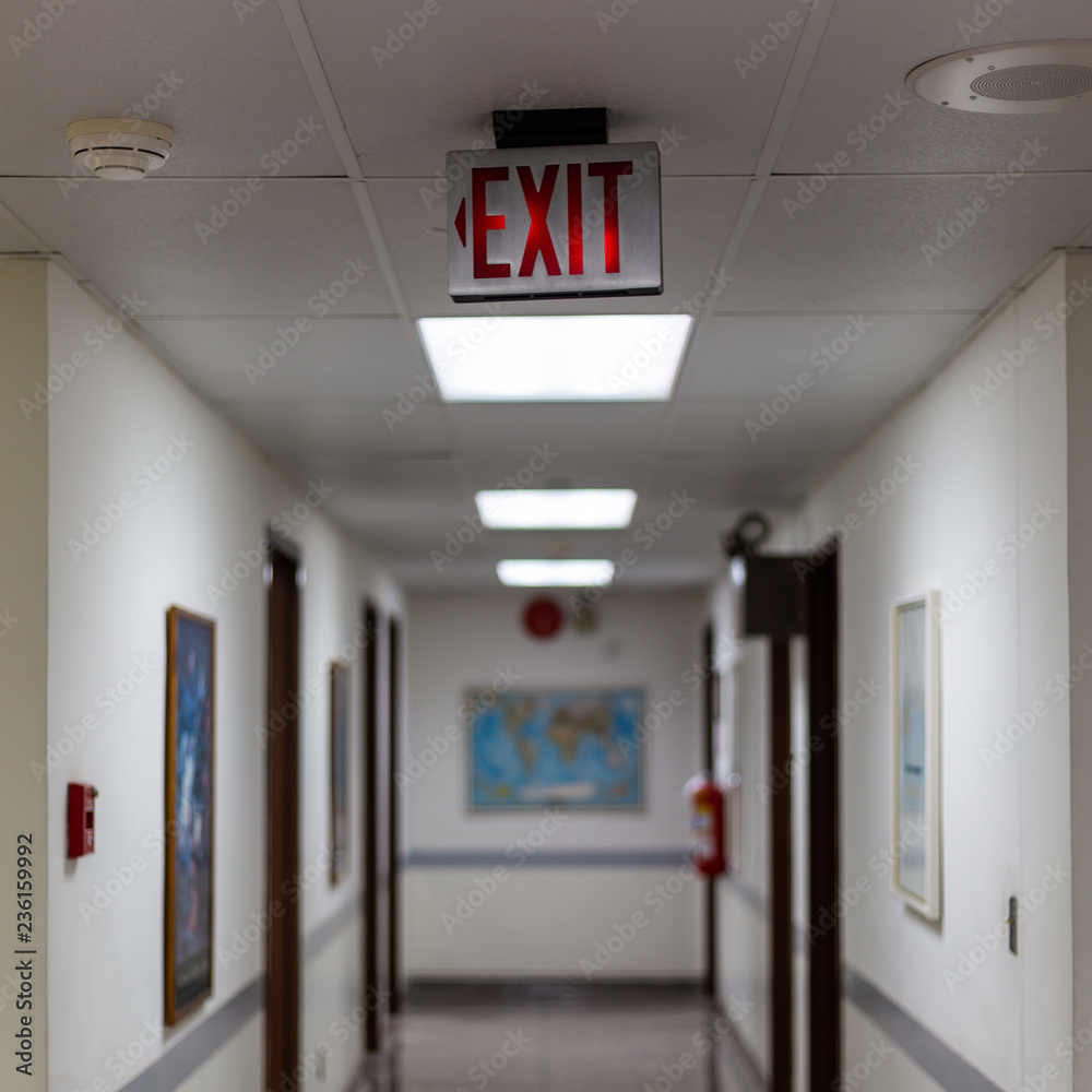 red emergency exit sign in the dark room. illuminated office exit sign ...