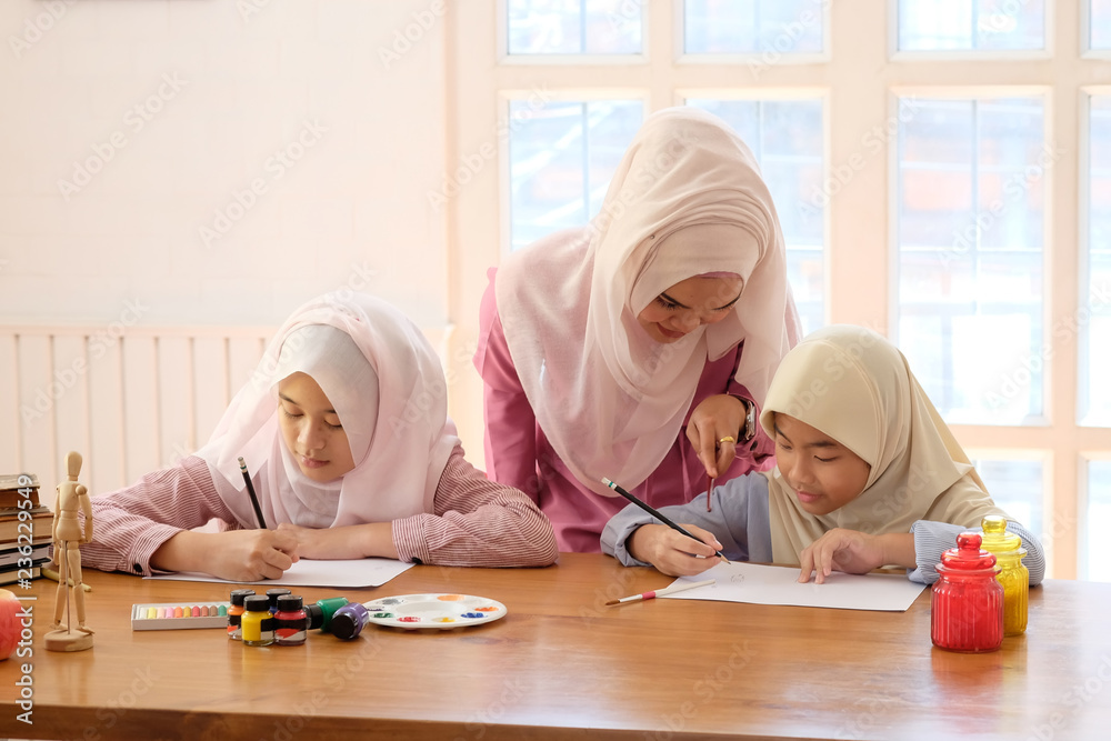 Adult muslim female teaching with art to learning a two child girl in ...