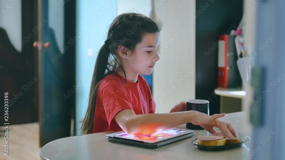 little girl playing digital tablet eating sandwiches. little girl ...