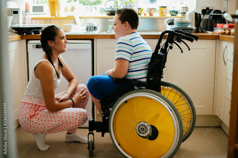 Sister helping her disabled brother in the kitchen Stock Photo | Adobe ...