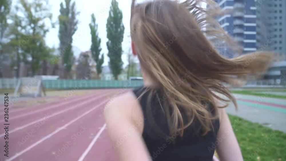 The camera moves behind the girl running outdoors A girl with long hair ...