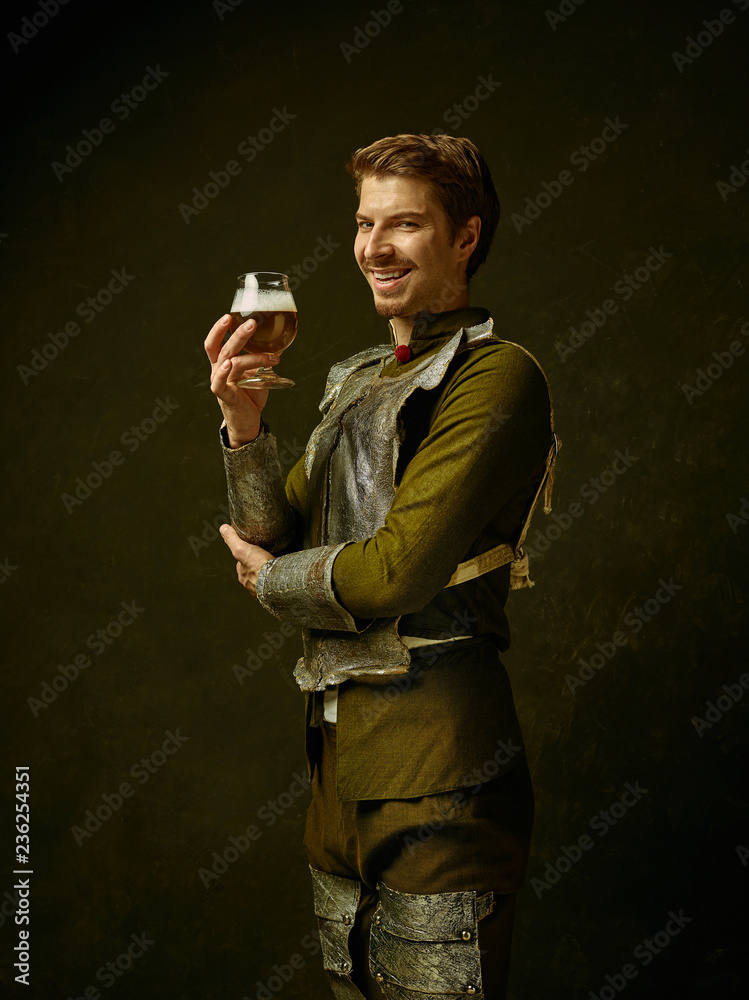 Medieval smiling happy knight with beer on dark studio background ...