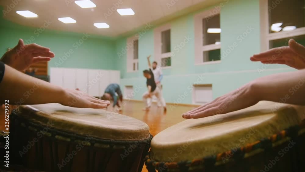 Playing a two musical instruments jembe or atabaque on background male ...