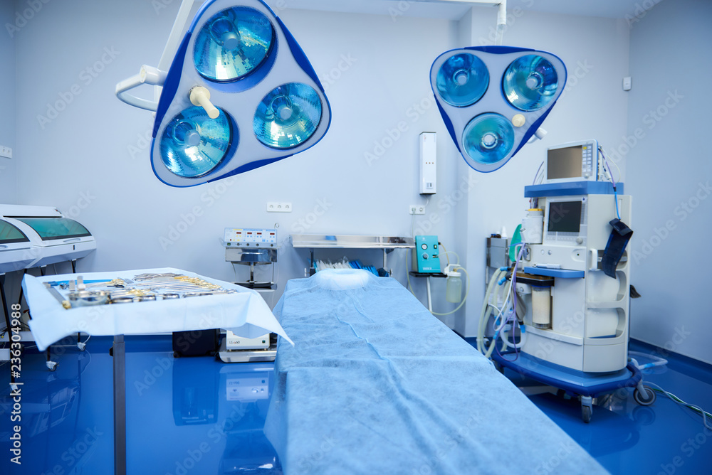 Sterile operating room with table of instruments and modern equipment ...