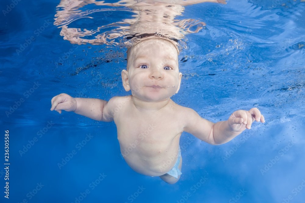 Little baby boy learns to swims underwater. Baby swimming underwater in ...