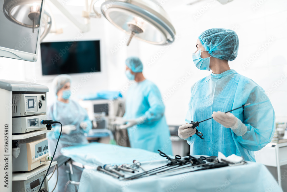 Waist up portrait of female medical worker in blue sterile gown ...