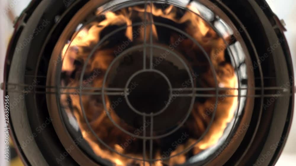 The flame breaks brightly through grid. Slow motion makes fire more ...