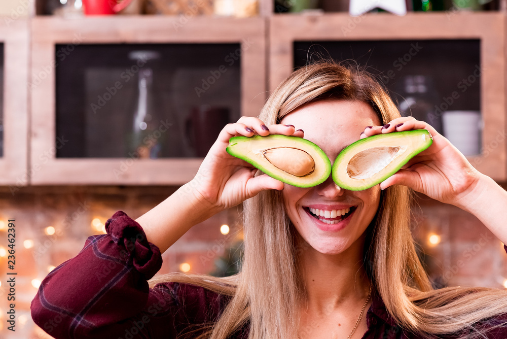Happy girl with avocado. Photo of blonde girl holding a half of avocado ...