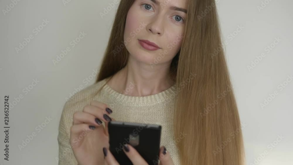 Smartphone woman using app on phone sitting with white wall background ...