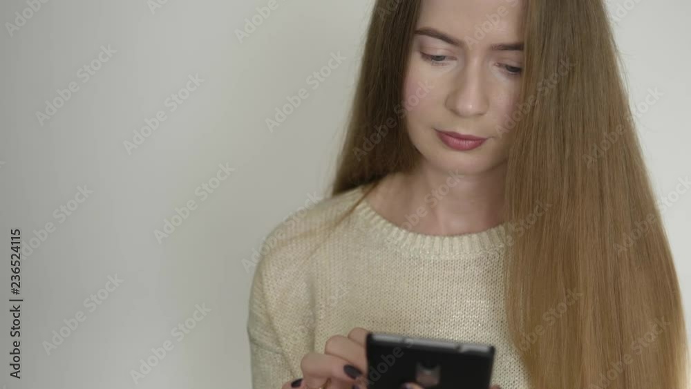 Smartphone woman using app on phone sitting with white wall background ...