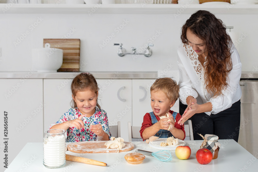Young children bake cake with their mother or nanny in the kitchen at ...
