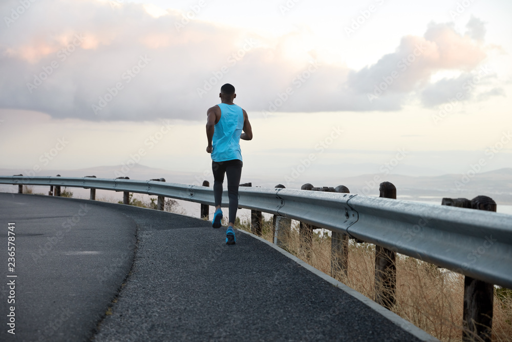 Active male runner runs along road, wears sportsclothes, covers ...