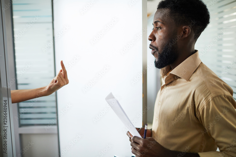 Embarrassed young African-american businessman looking at rude gesture ...