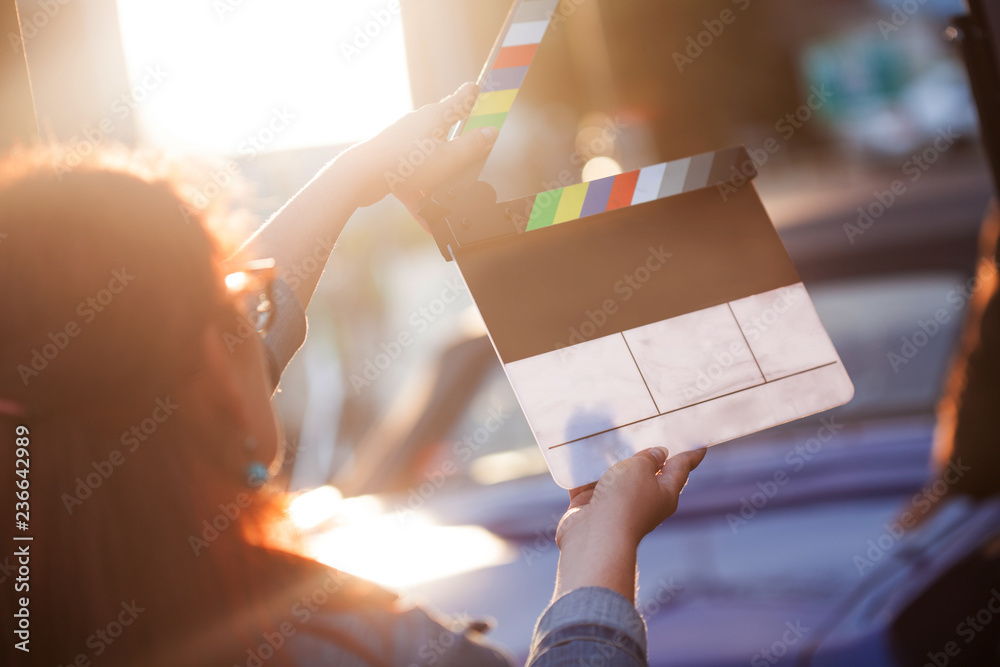 Filming on location. Woman holding a clapperboard in front of the ...