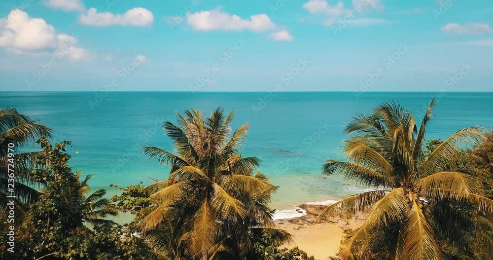 Fly over tropical trees and sandy beach over beautiful lagoon sea water ...