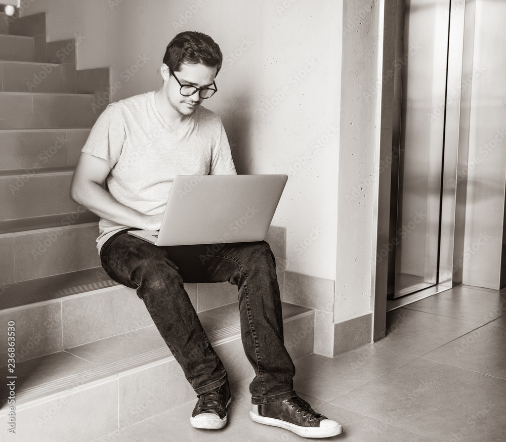 Handsome young freelancer man using laptop computer sitting at stairs ...