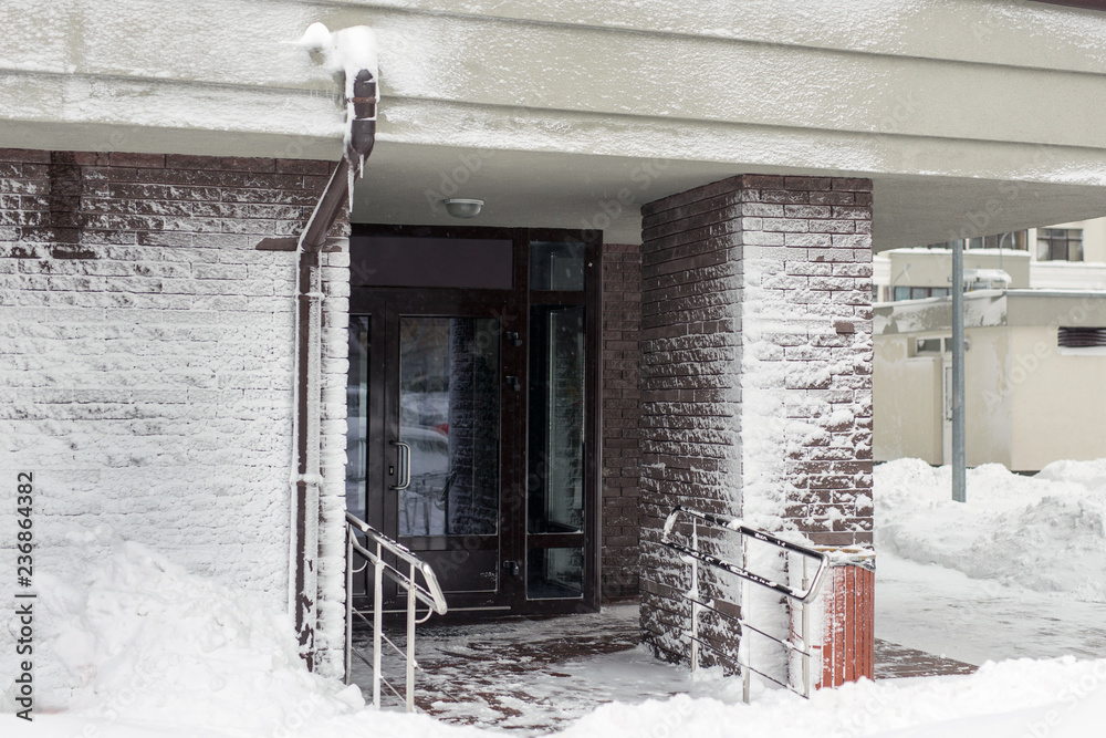 Entrance of modern high-rise apartment building covered with snow and ...