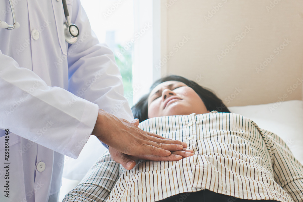 Doctor examining stomach of woman patient and pressing hands on her ...
