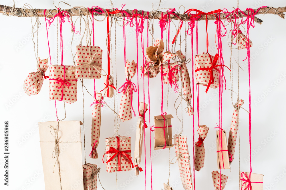 Handmade advent calendar hanging on a white wall. Gifts wrapped in ...